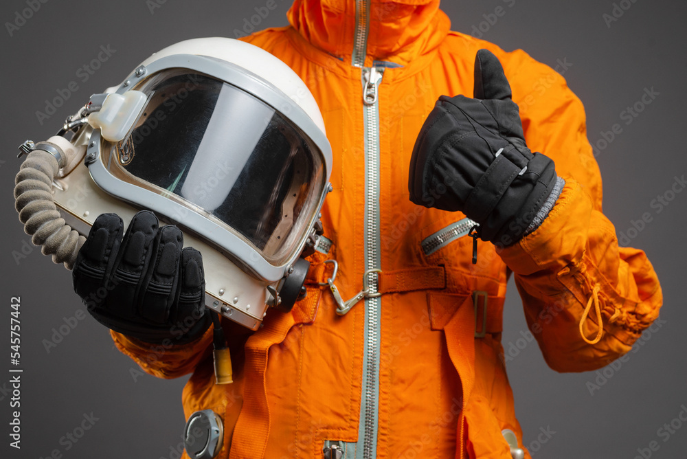 Astronaut is standing in the space suit and helmet in hand and showing ...