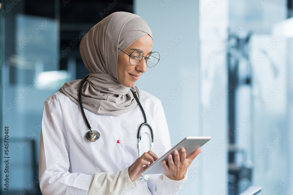 Close-up photo. A young Arab woman, a Muslim doctor is standing in the ...