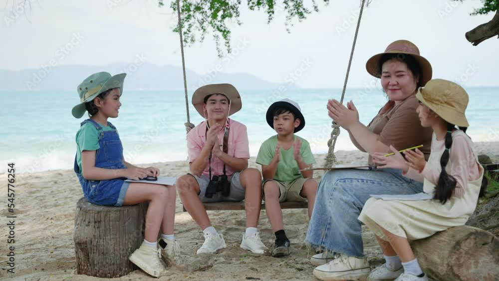 In an outdoor excursion class at the beach, a group of children ...