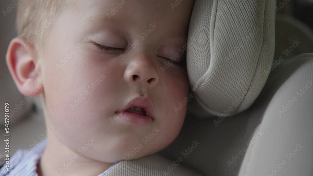 close-up face sleeping child boy inside vehicle in car seat safety belt ...