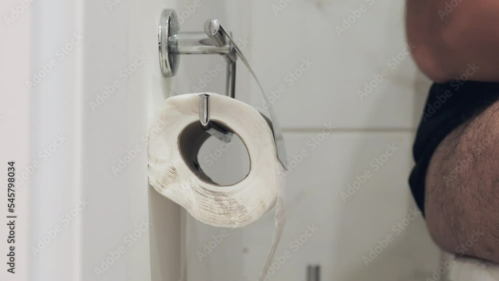 Using toilet paper in a public restroom. Wall mounted metal bumf holder ...