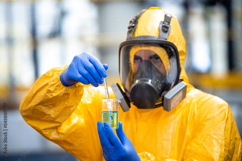 Professional chemical worker in protection suit and gas mask handling ...