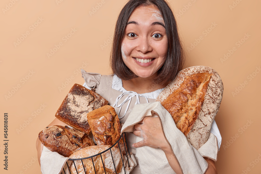 Horizontal shot of beautiful cheerful female baker poses with variety ...