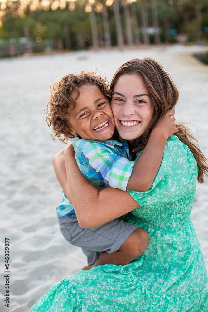Portrait of two beautiful diverse children smiling and hugging each ...