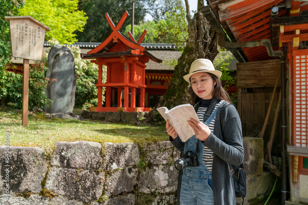 Asian Japanese female traveler reading travel guidebook to learn about ...