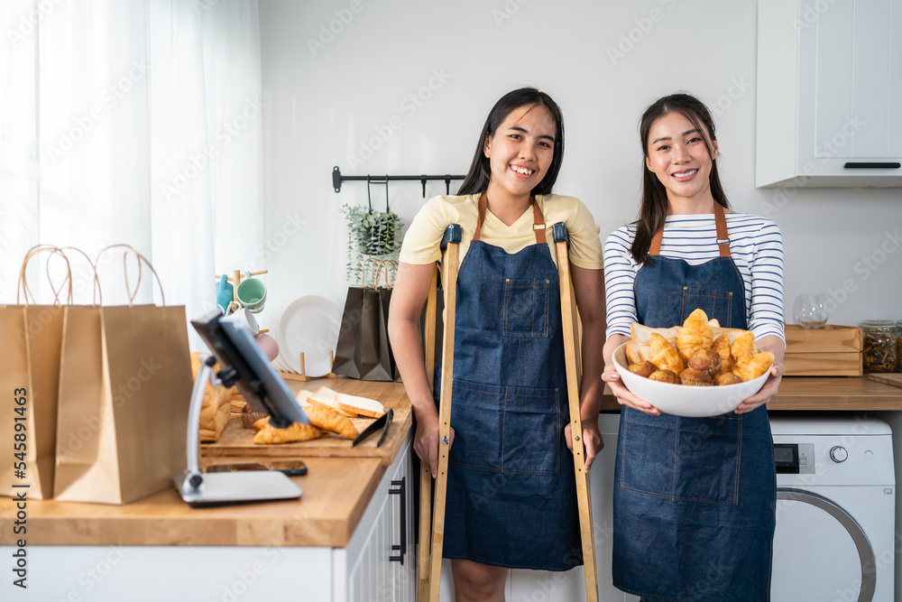 Portrait of Asian female amputee leg stand in kitchen with her friend ...