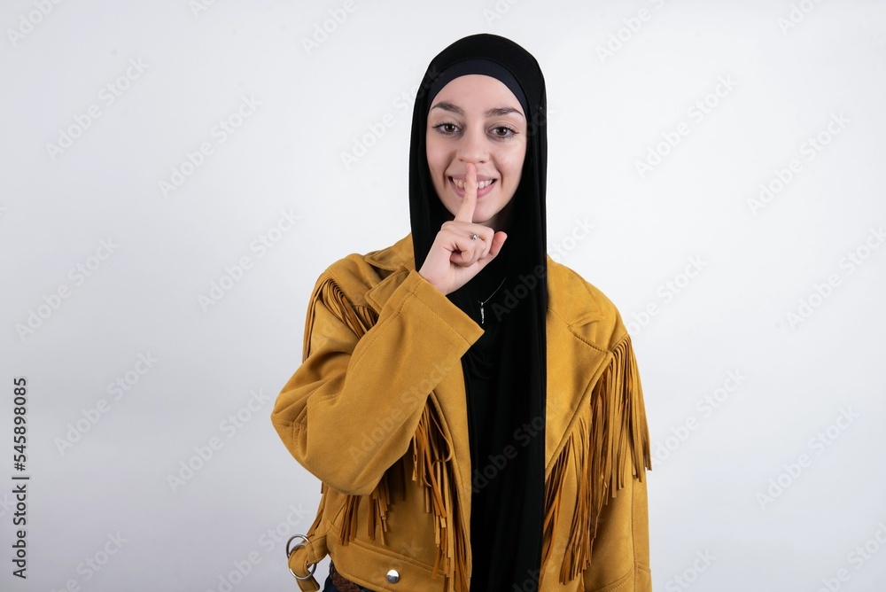 Smiling young beautiful muslim woman wearing hijab and yellow jacket ...