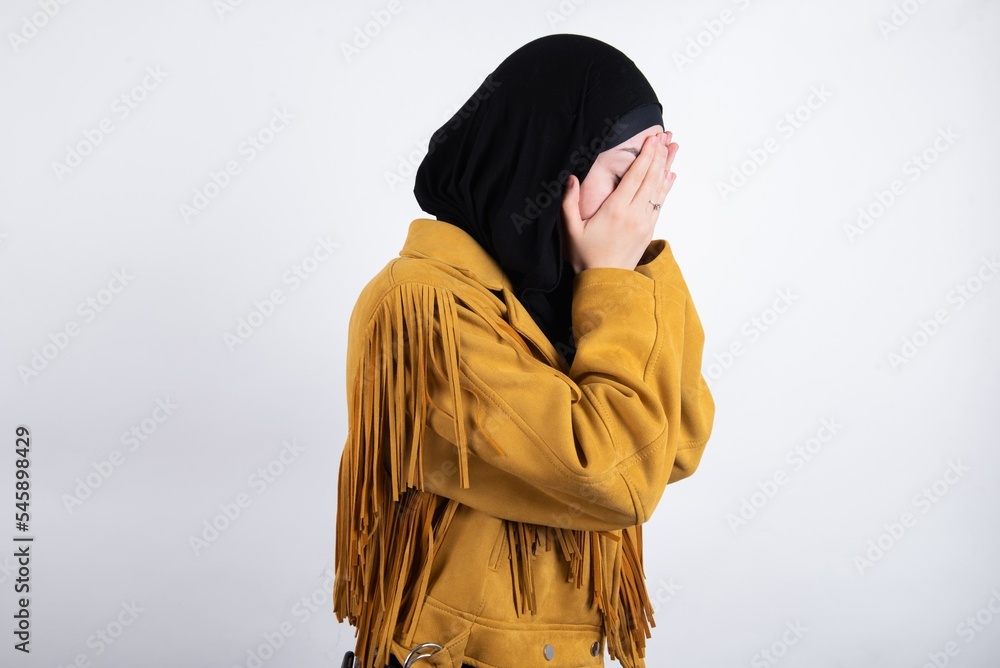 Sad young beautiful muslim woman wearing hijab and yellow jacket over ...
