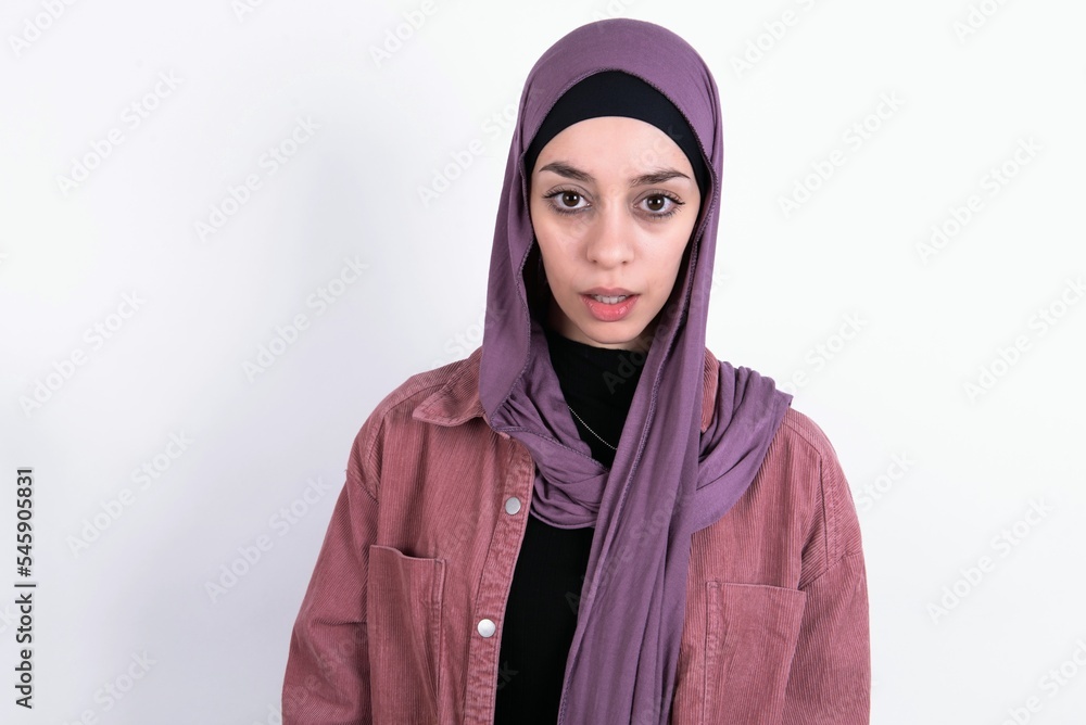Shocked young beautiful muslim woman wearing hijab against white ...
