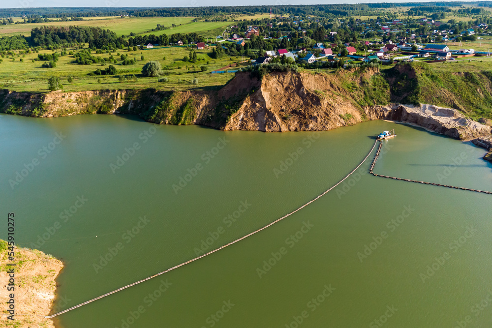Sand mining in a flooded sand pit with a floating dredger, aerial view ...