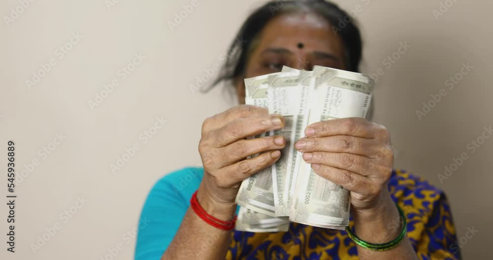 Indian woman counting new Indian 500 rupee notes against white wall at ...