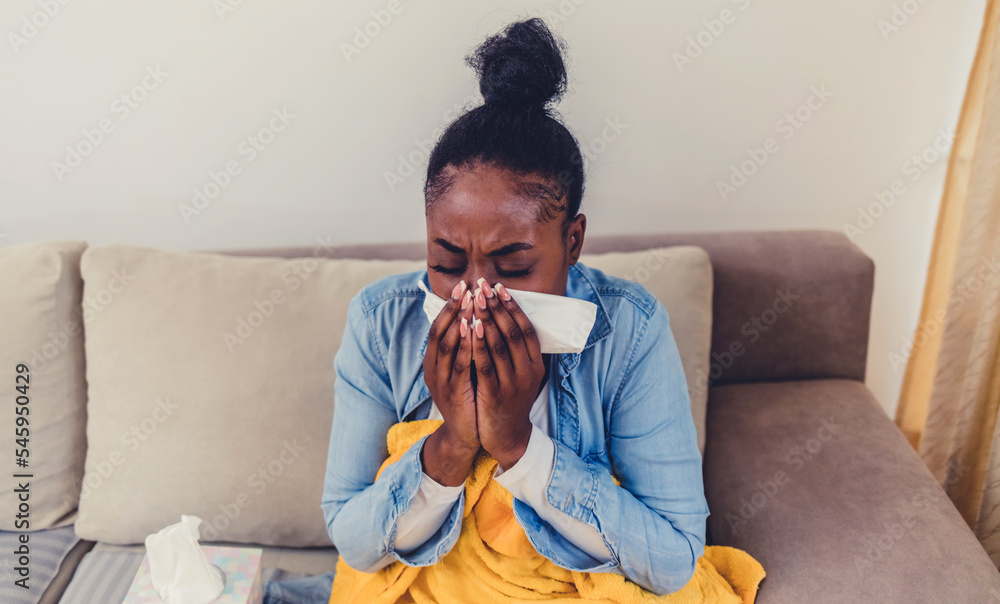 Sick woman covered with a blanket lying in bed with high fever and a ...