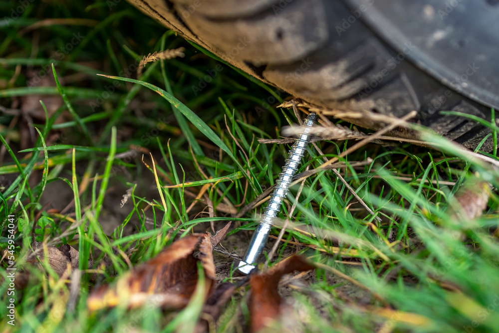 large metal self-tapping screw stands under the wheel of a car, concept ...