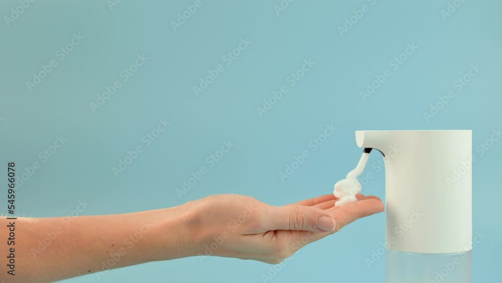Hands of young woman press the touch button of an automatic soap ...