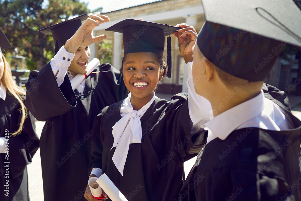 Young African American girl graduating from university. Happy diverse students having fun on ...