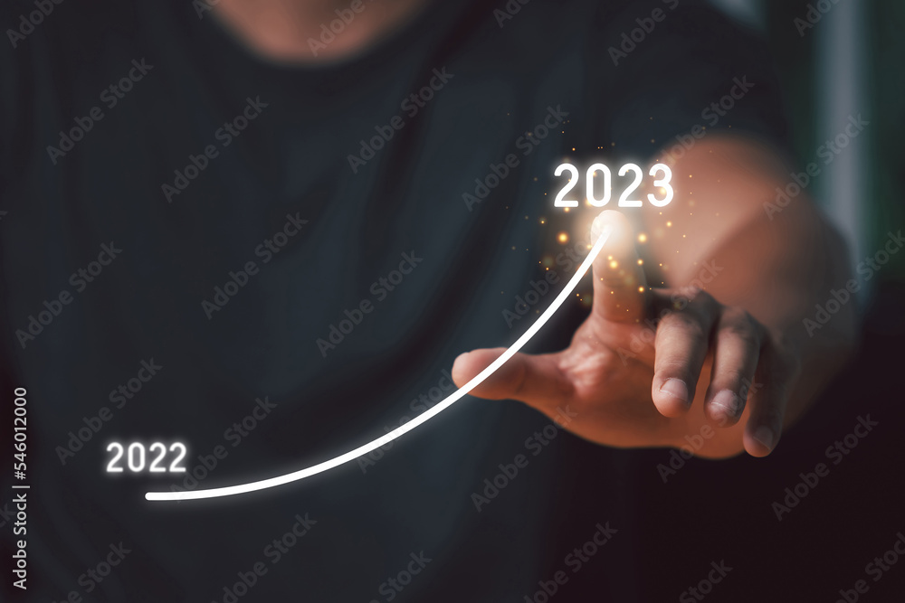Man's hand pointing graph of success in 2023 year. The man plans to ...