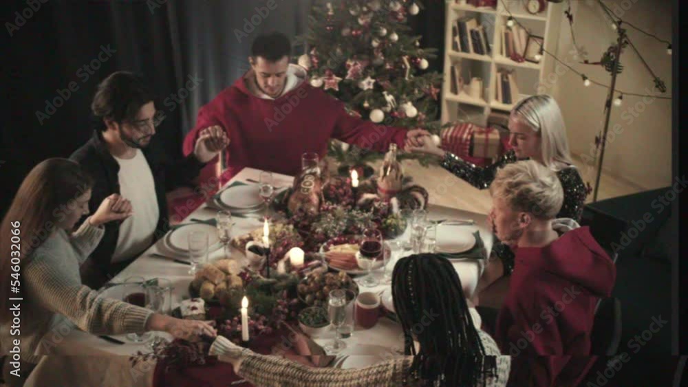 Friends holding hands and praying before dinner, new year tradition ...