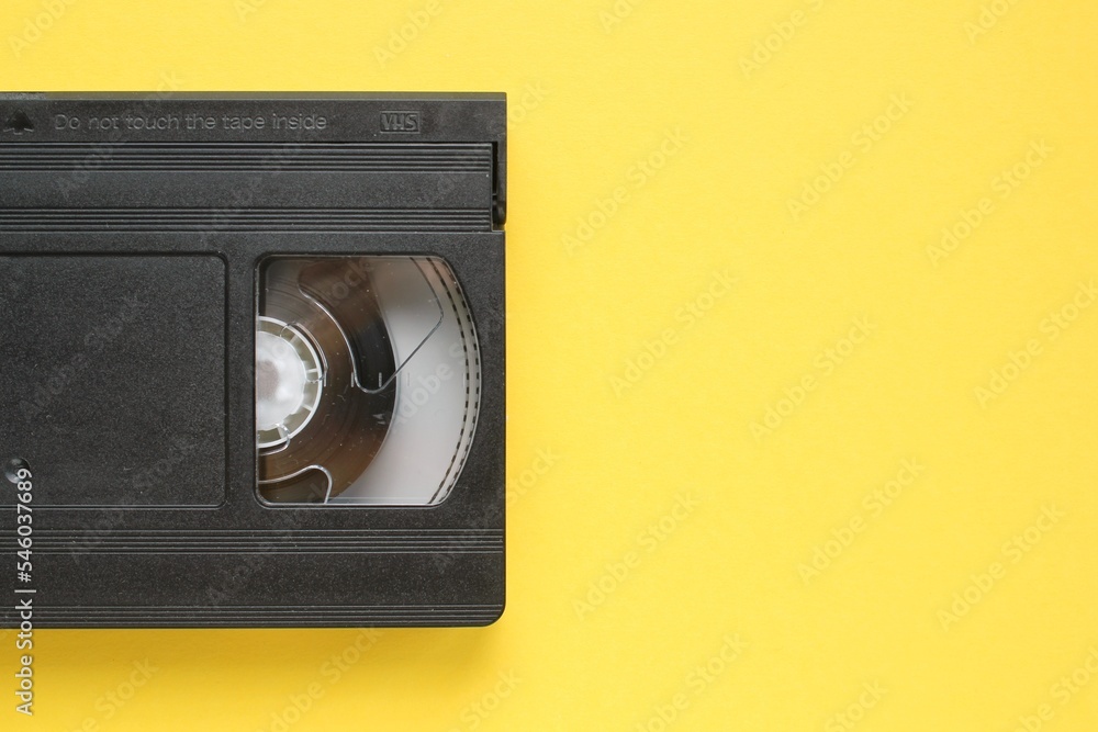 Black VHS videotape recorder cassette on yellow background. Old ...