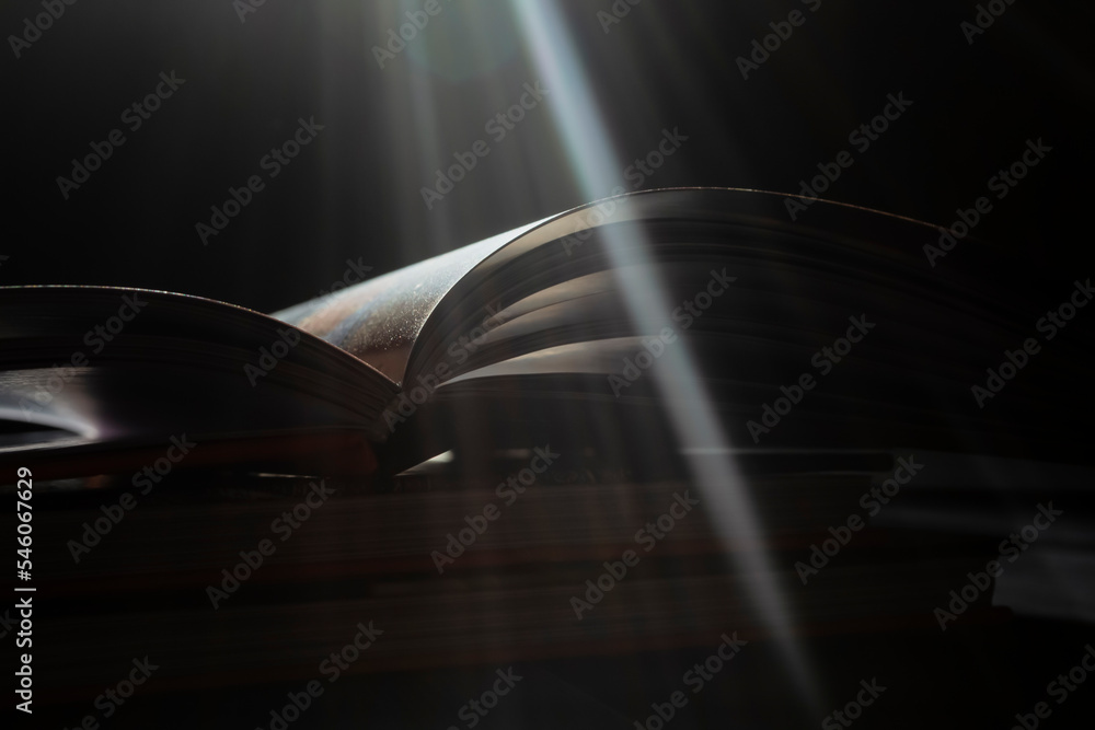 Rays of light fall on the opened book. The book is illuminated by light ...