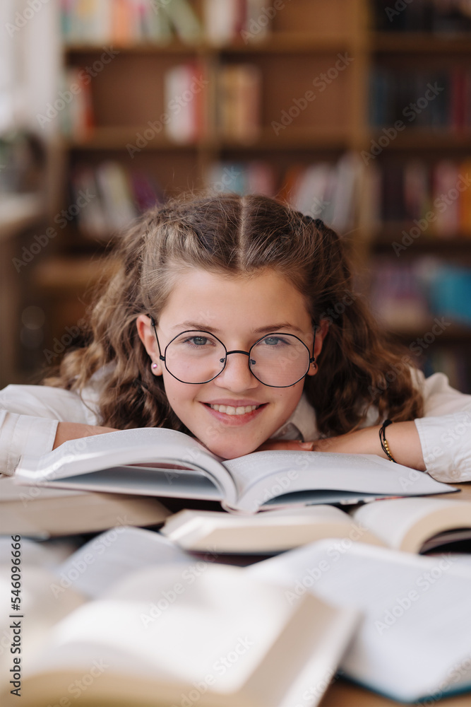 Attractive happy young girl student studying at the college library ...