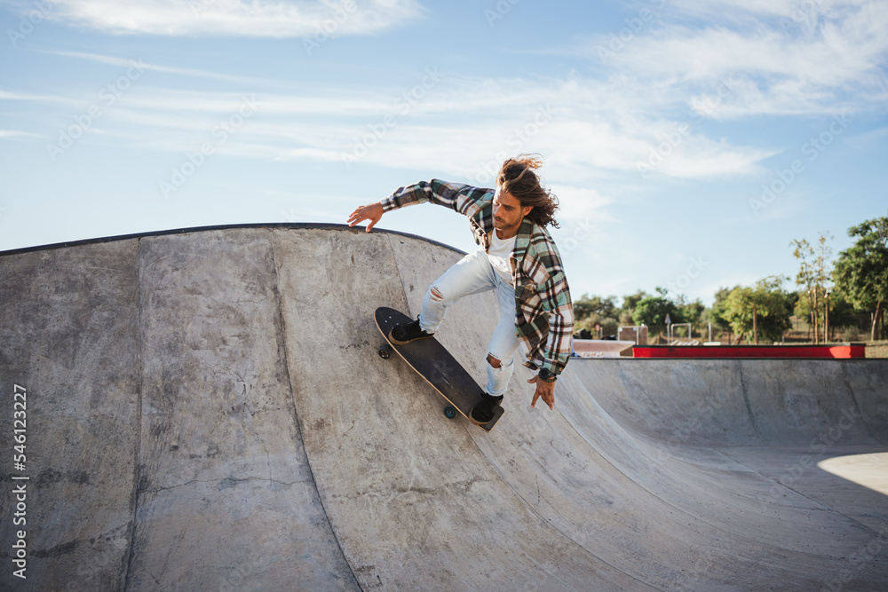 Professional man going up a wall of a skate park pool while ...