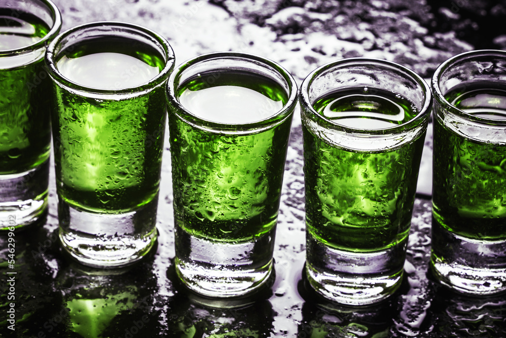 Glass vodka shots. Green alcohol. Many alcohol drinks in a row texture ...