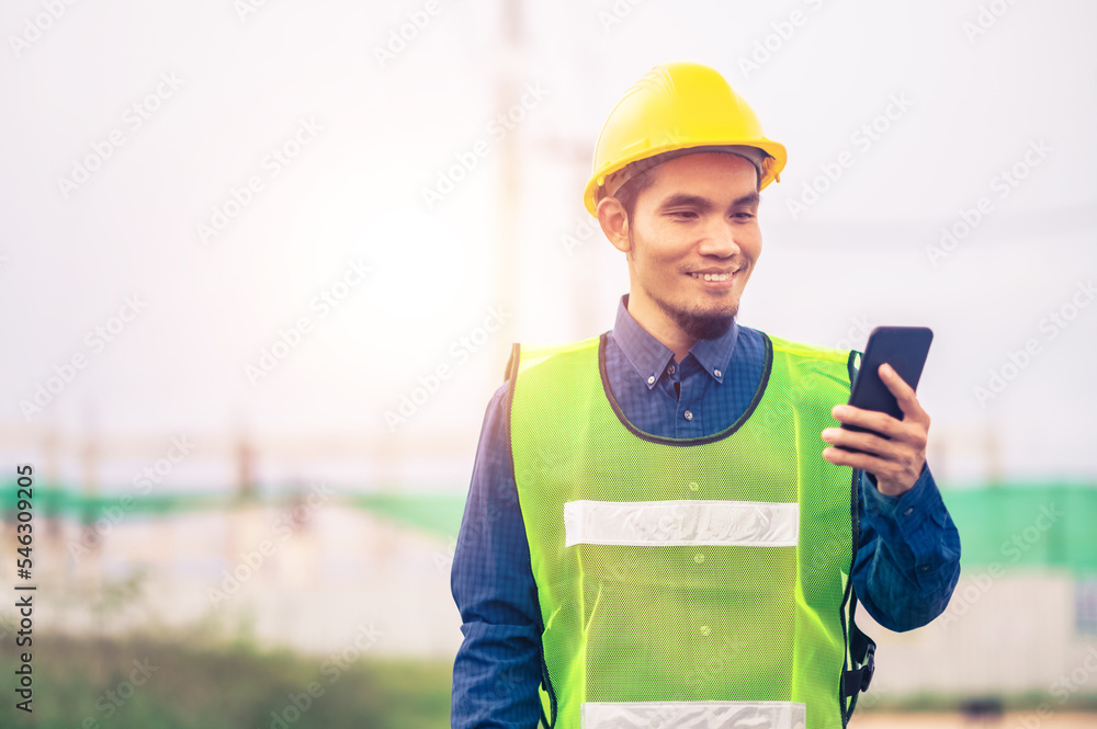Asian Engineer holding smartphone standing outdoor on site construction ...