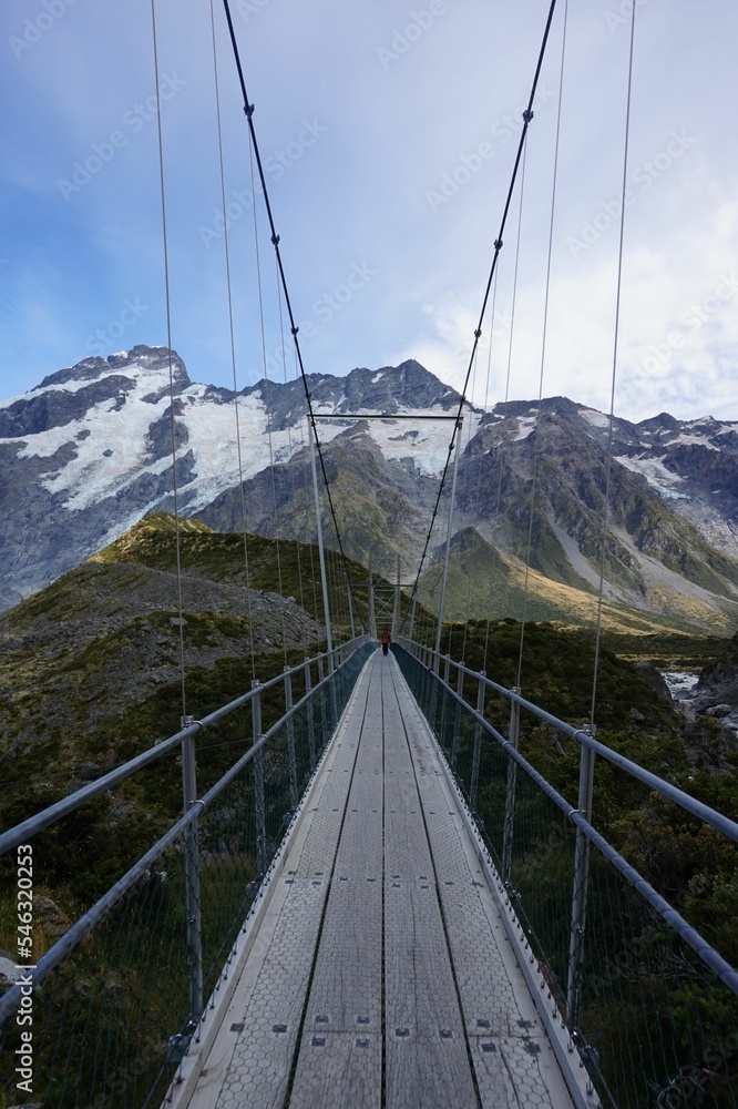 Vertical high-angle of a wooden suspended bridge leading to the ridged ...
