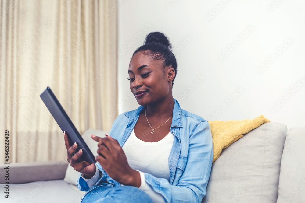 Working from home. A young woman using a digital tablet to read/watch ...
