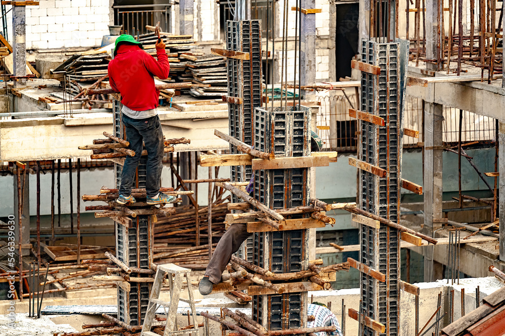 A construction worker nails wood poles as temporary supports to steel ...