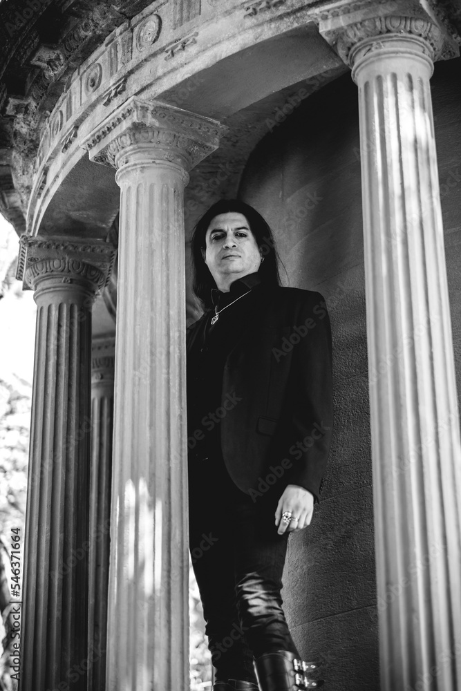 Dark gothic man with long hair in large ancient abandoned mausoleum in ...