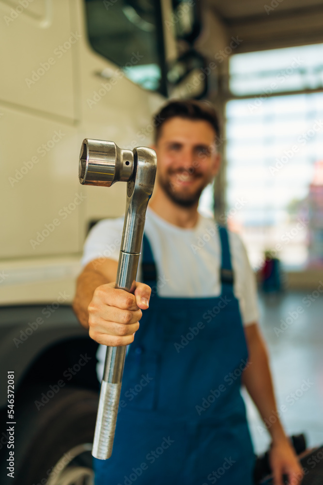 Mechanic is standing in his workshop and holding tools. He is ready to ...