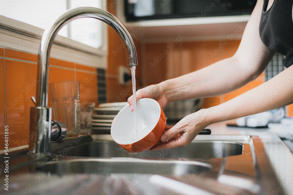 Woman washing dishes in kitchen sink, close up of hands rinsing bowl ...