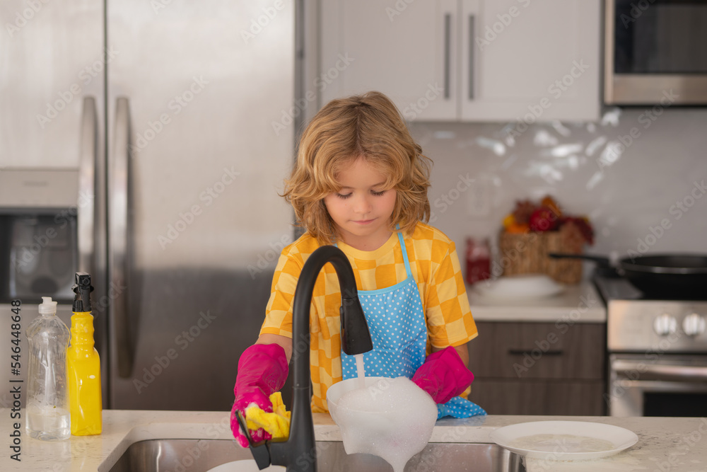 Kid washing dishes in the kitchen interior. Child helping with ...