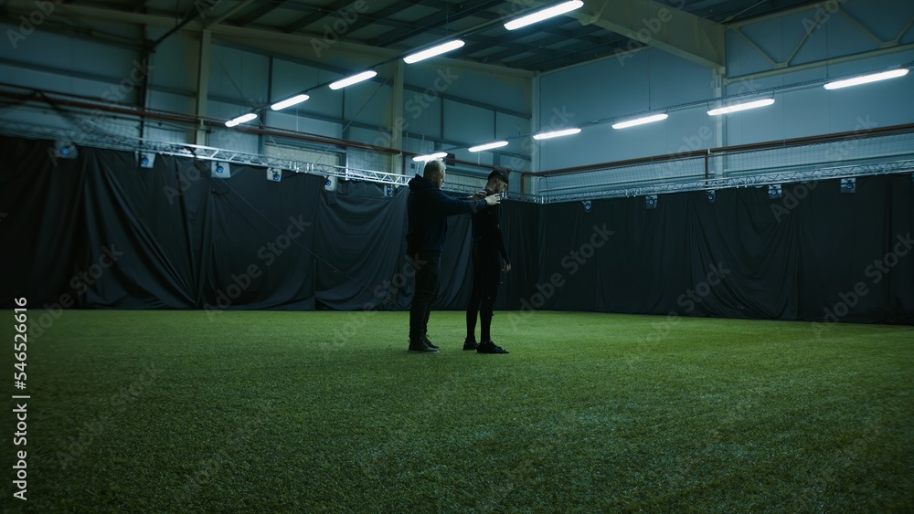 BTS of filmmaking. Technician preparing an actor for motion capture acting, placing markers over ...
