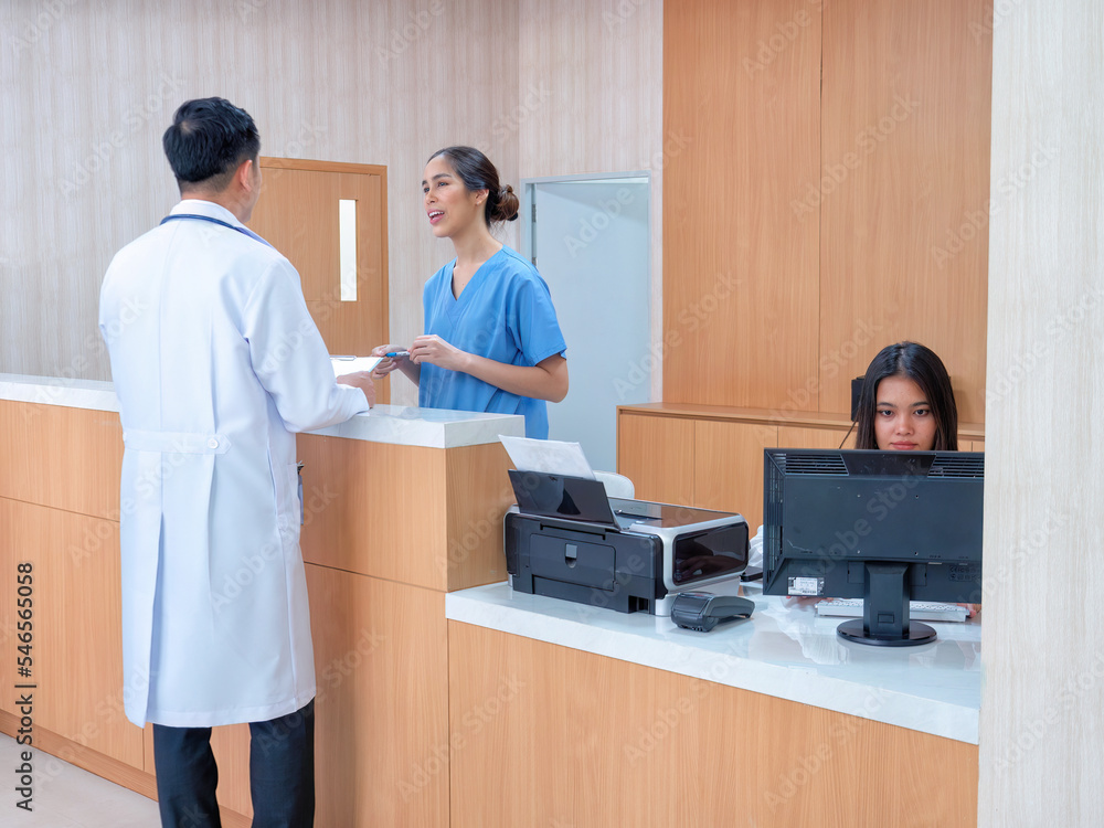 At hospital information counter doctor speaking to administrative crew ...