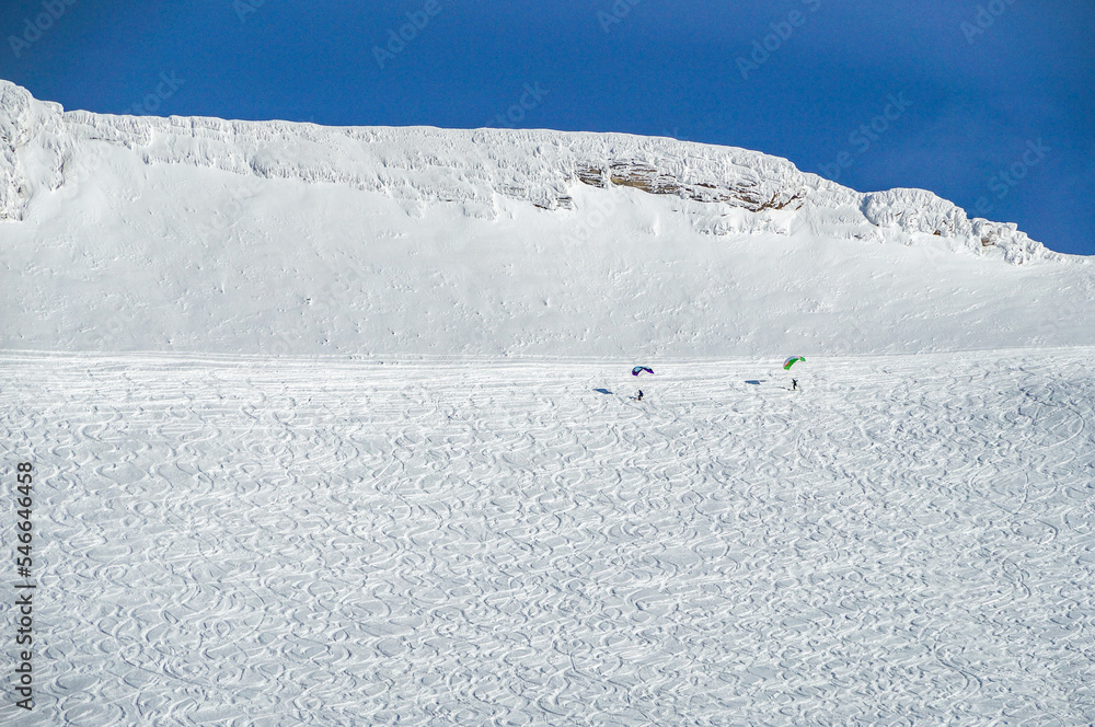 Speedflyers riding on steep ski slope in breathtaking winter mountain ...