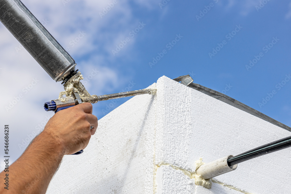 The builder insulates the walls of the house with polystyrene foam and ...