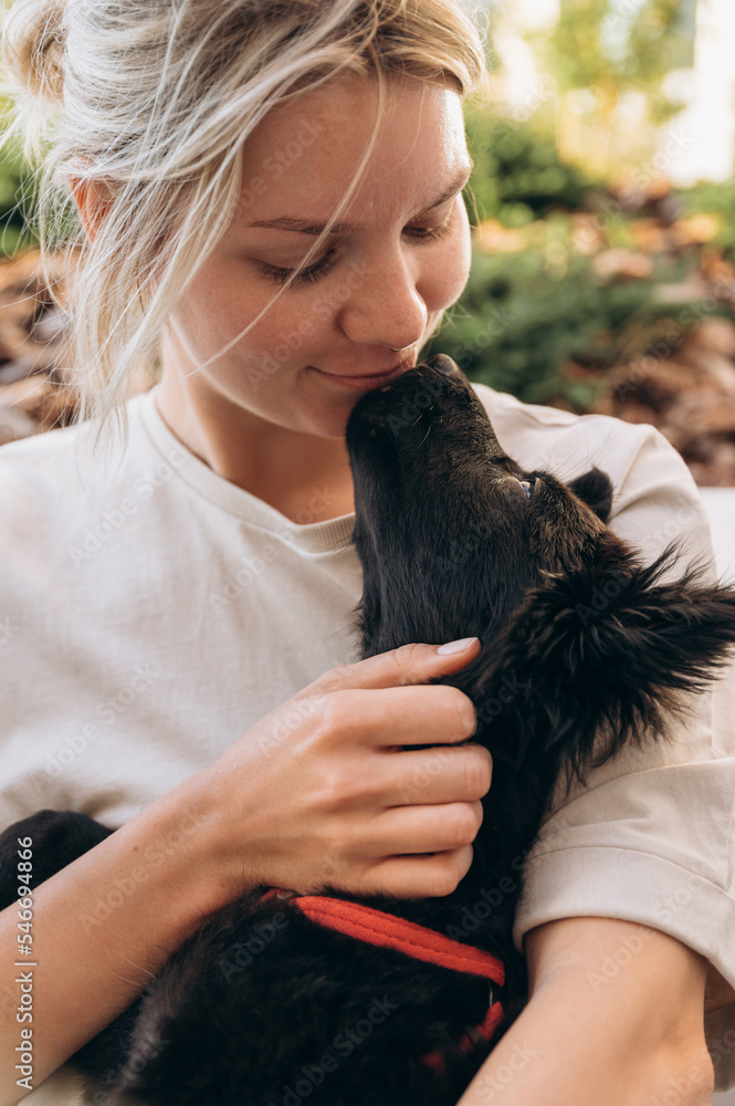 Young female owner kissing adorable dog in park Stock Photo | Adobe Stock