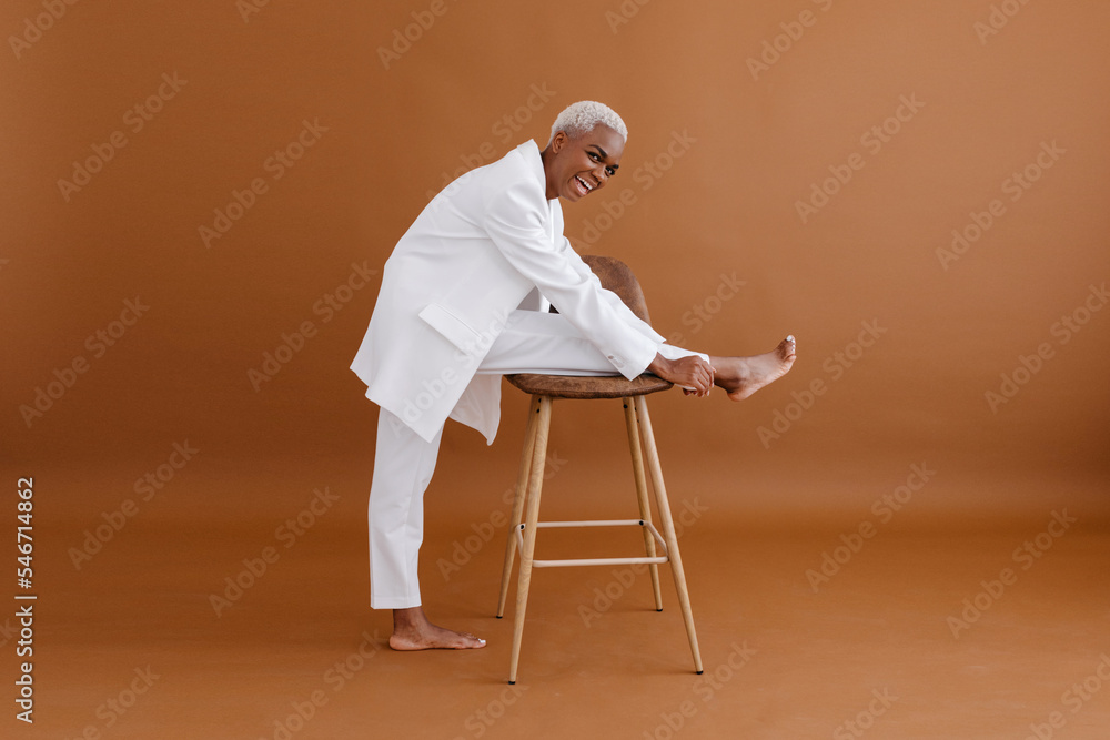 Glad black female model with leg lying on stool Stock Photo | Adobe Stock