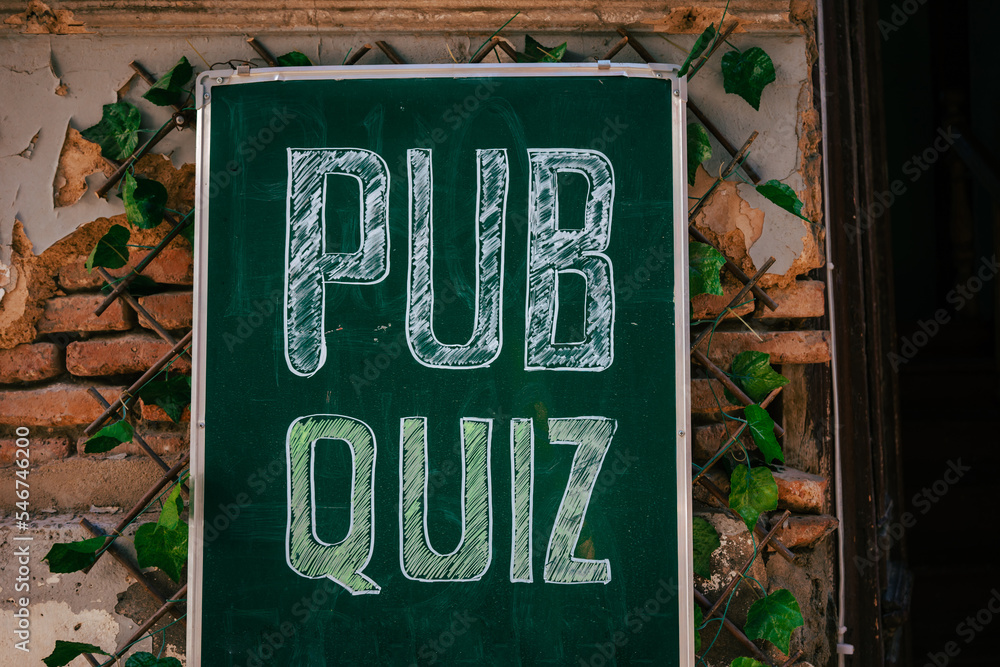 Green chalk board with the inscription ' PUB QUIZ ' in front of an open ...