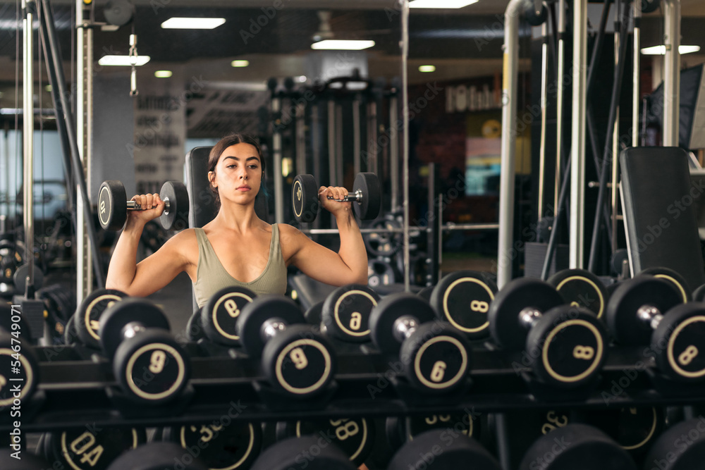 Foto de Strong woman training with dumbbells in the gym do Stock ...