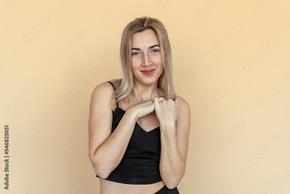 Lack of confidence. Shy young woman feels awkward stands over beige ...