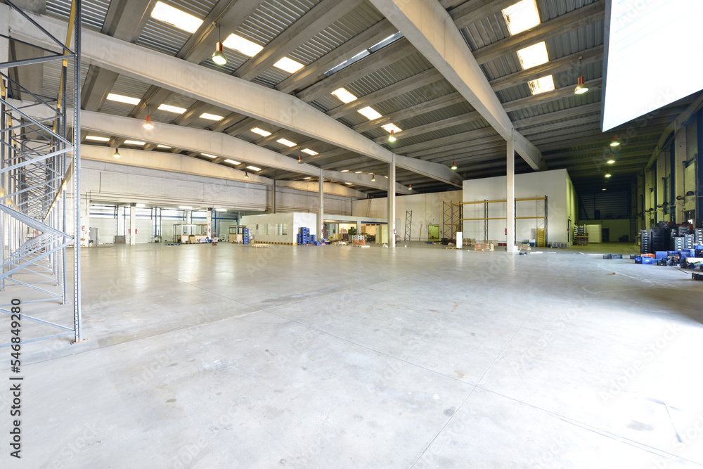 A large empty industrial warehouse with concrete floors and skylights ...