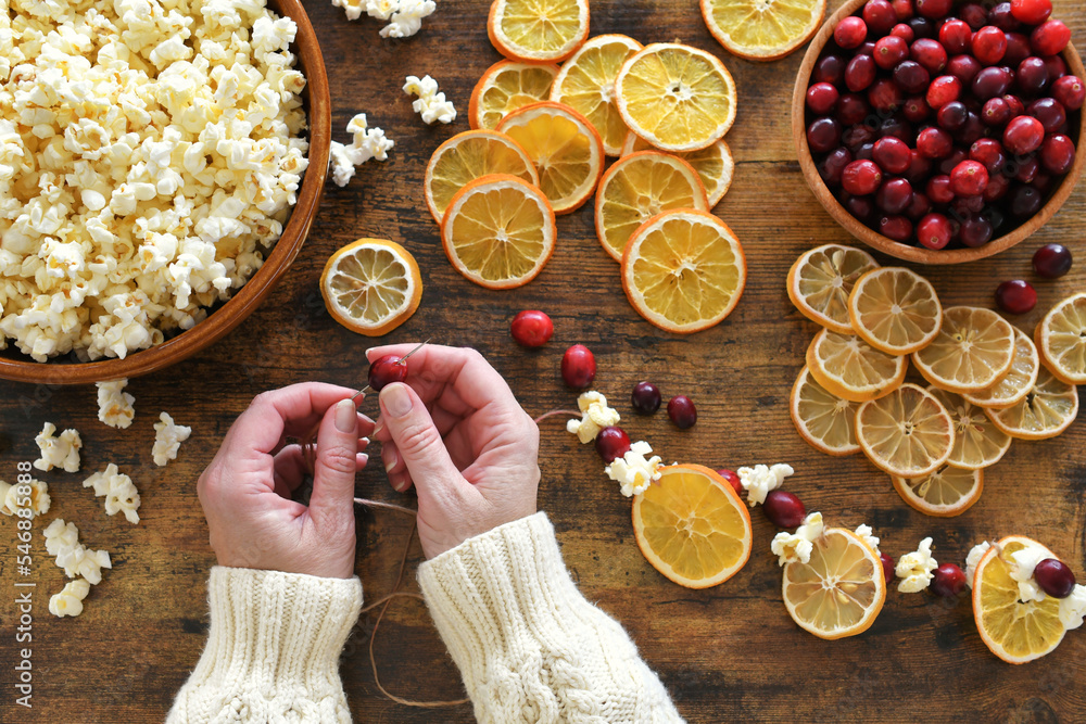 Female making homemade Christmas garland by stringing popcorn ...
