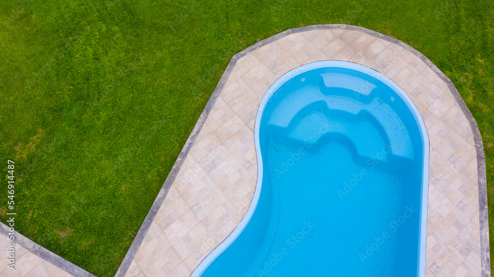 Aerial view of a swimming pool with wavy and curved shapes. Around the ...
