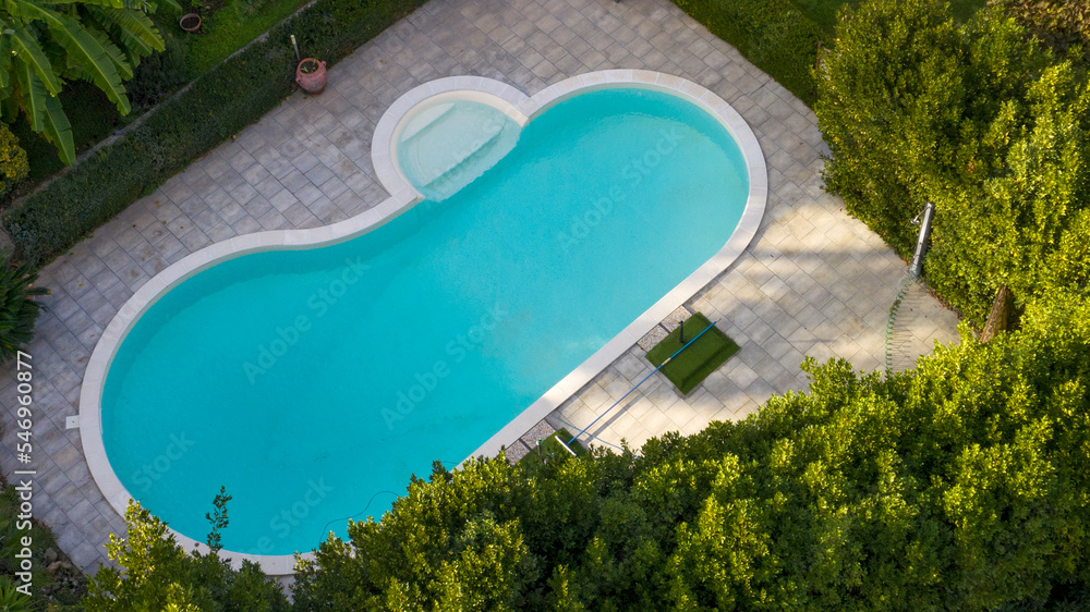 Aerial view of a swimming pool with wavy and curved shapes. Around the ...