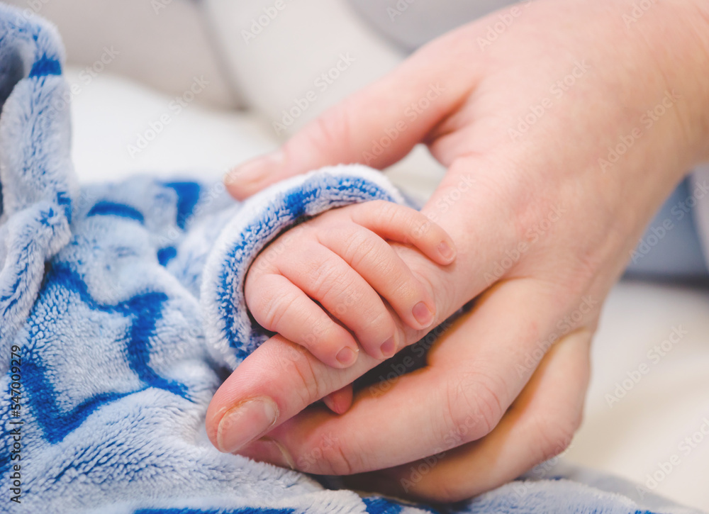 Newborn baby touching his mother hand. Mother uses her hand to hold her ...