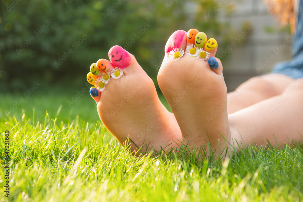 Teenage girl with drawn smiling faces and chamomiles between toes ...