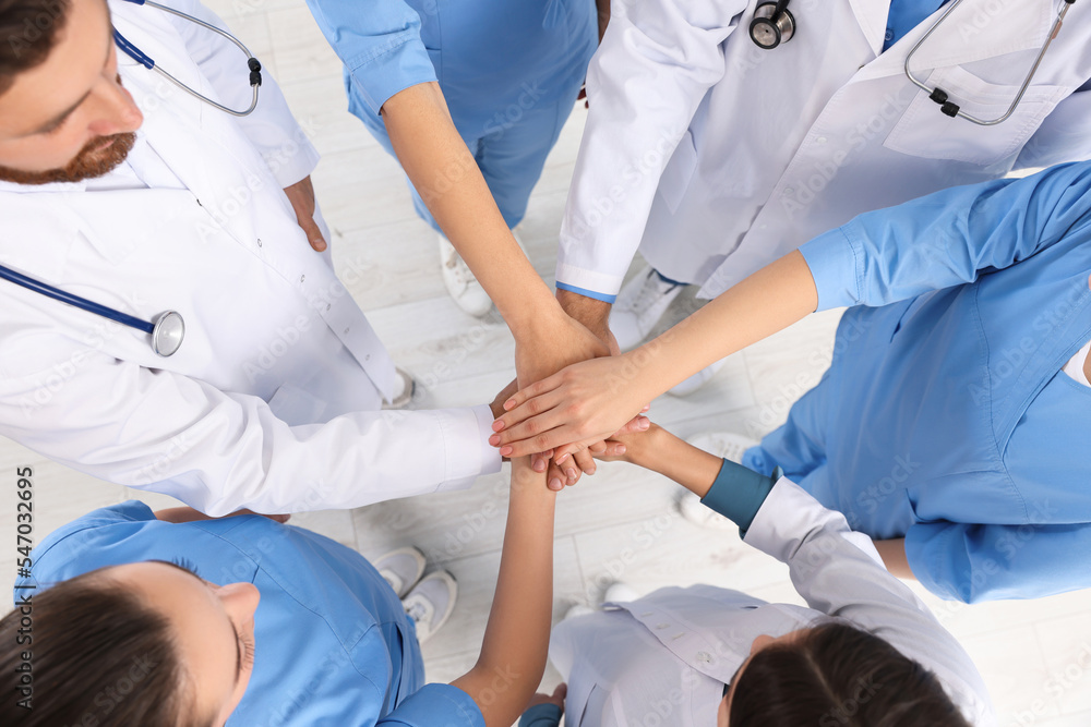 Team of medical doctors putting hands together indoors, above view ...